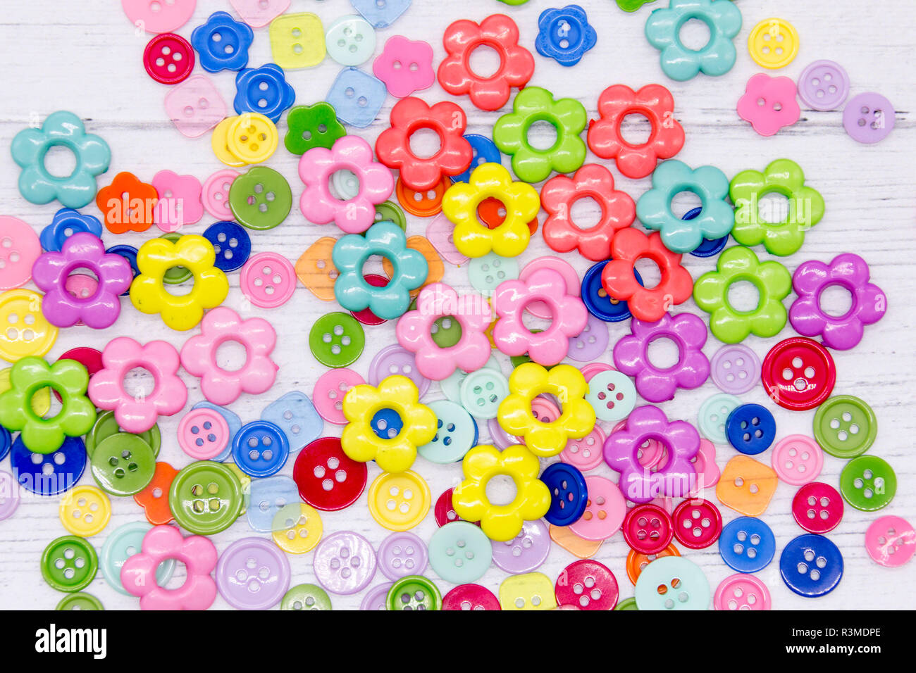 A collection of colourful sewing buttons and beads on a painted white ...