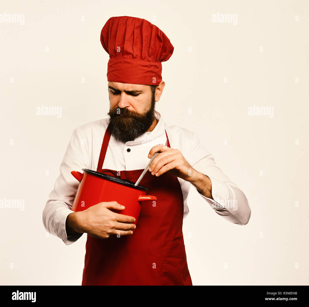 Man with beard holds red pot on white background. Cook with curious ...