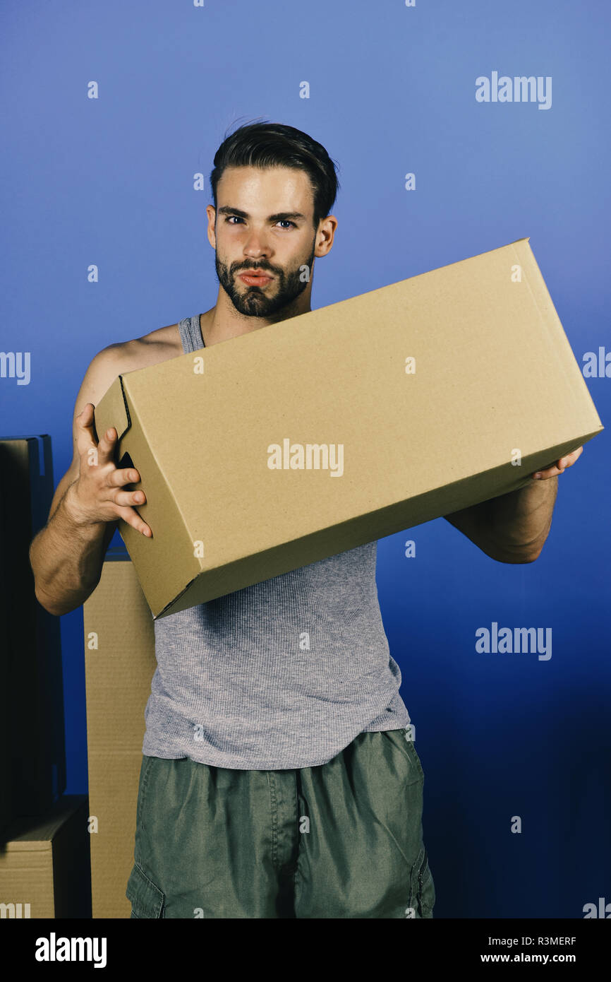 Guy with carton isolated on blue background. Delivery and moving in ...