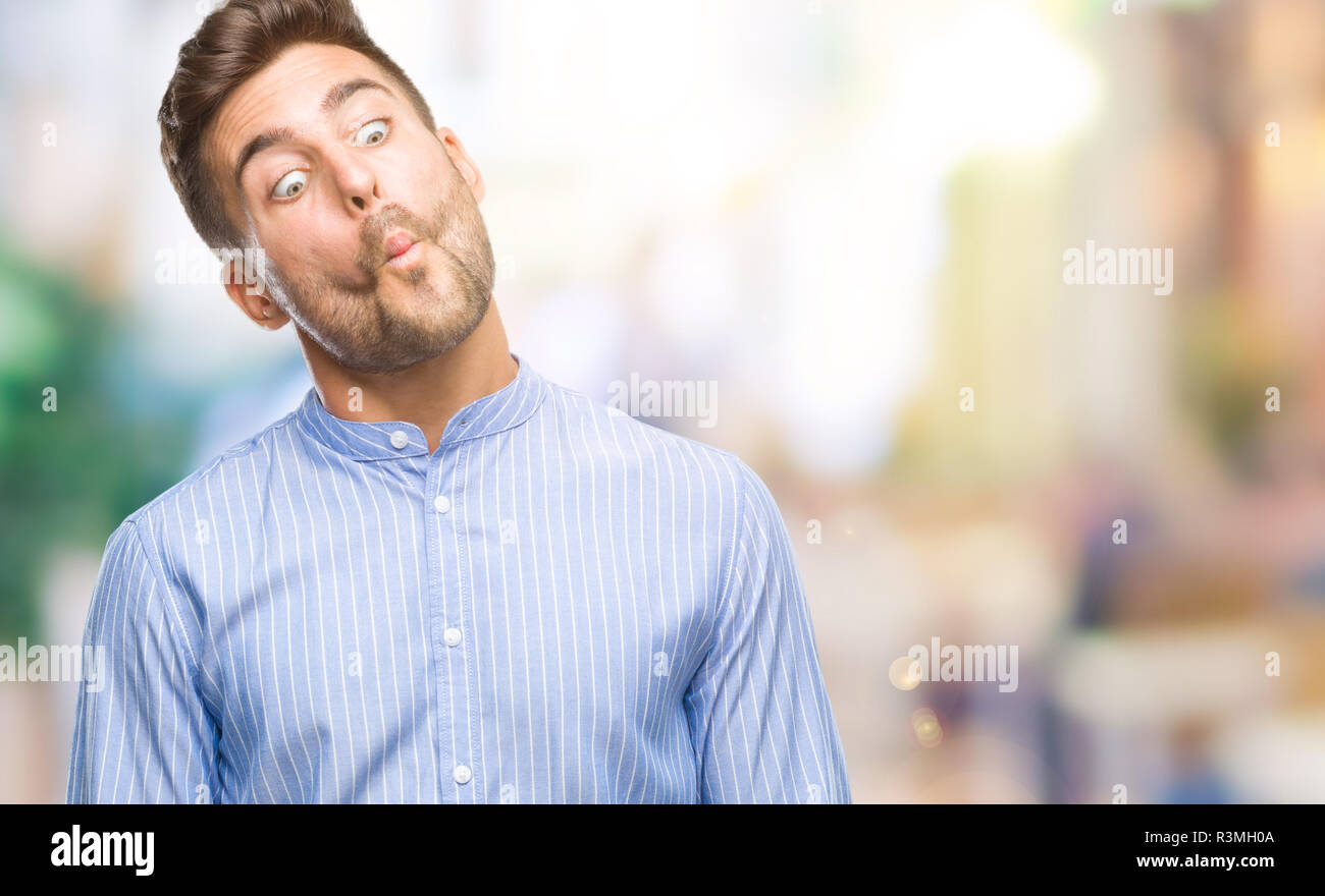 Young handsome man over isolated background making fish face with lips ...