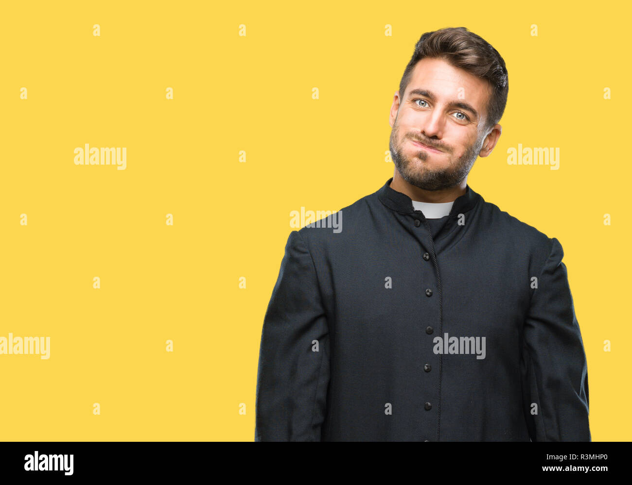Young catholic christian priest man over isolated background puffing ...