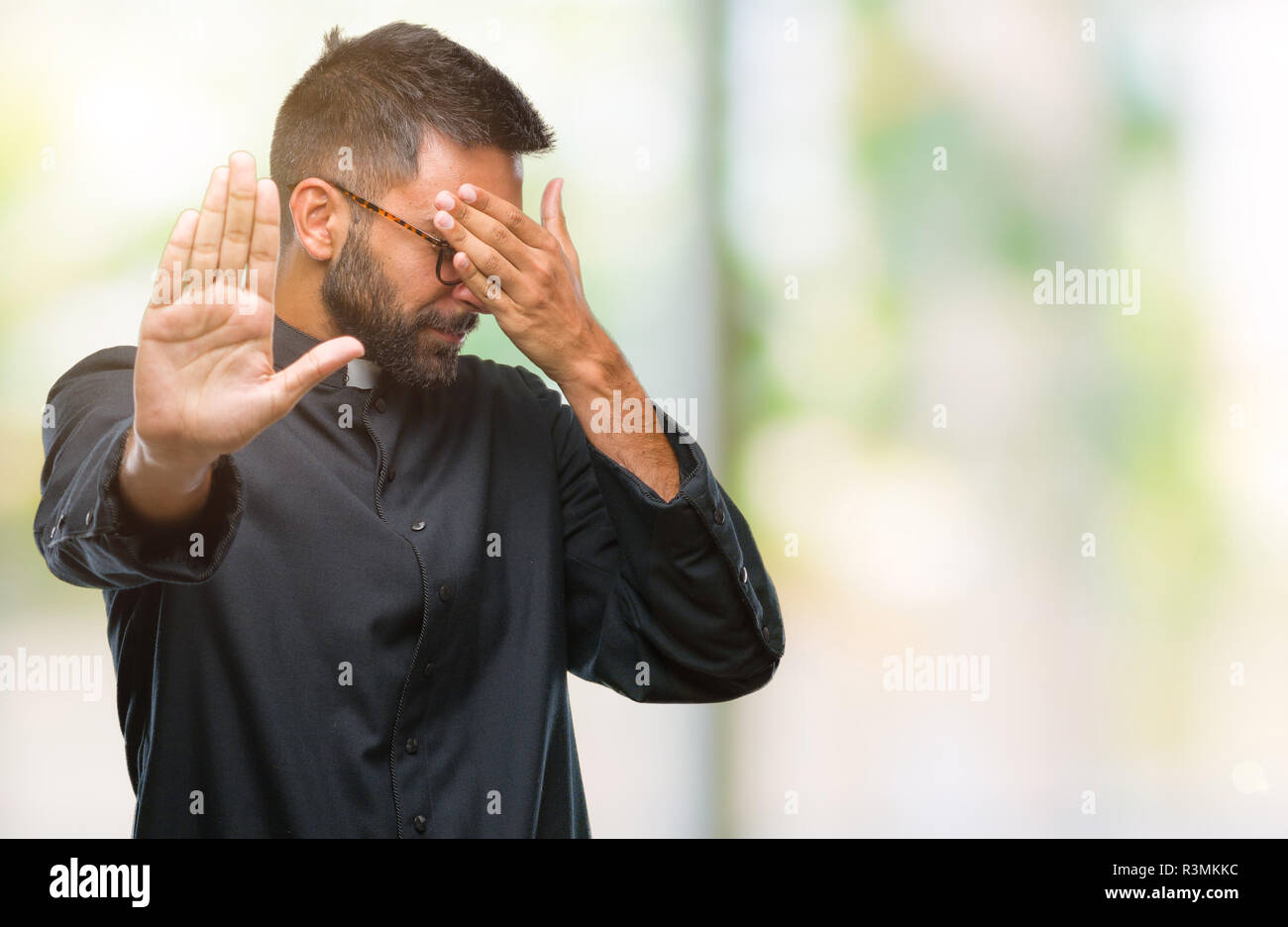 Adult hispanic catholic priest man over isolated background covering ...