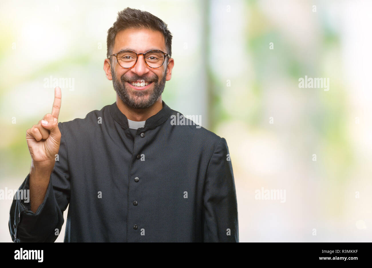 Adult hispanic catholic priest man over isolated background showing and ...