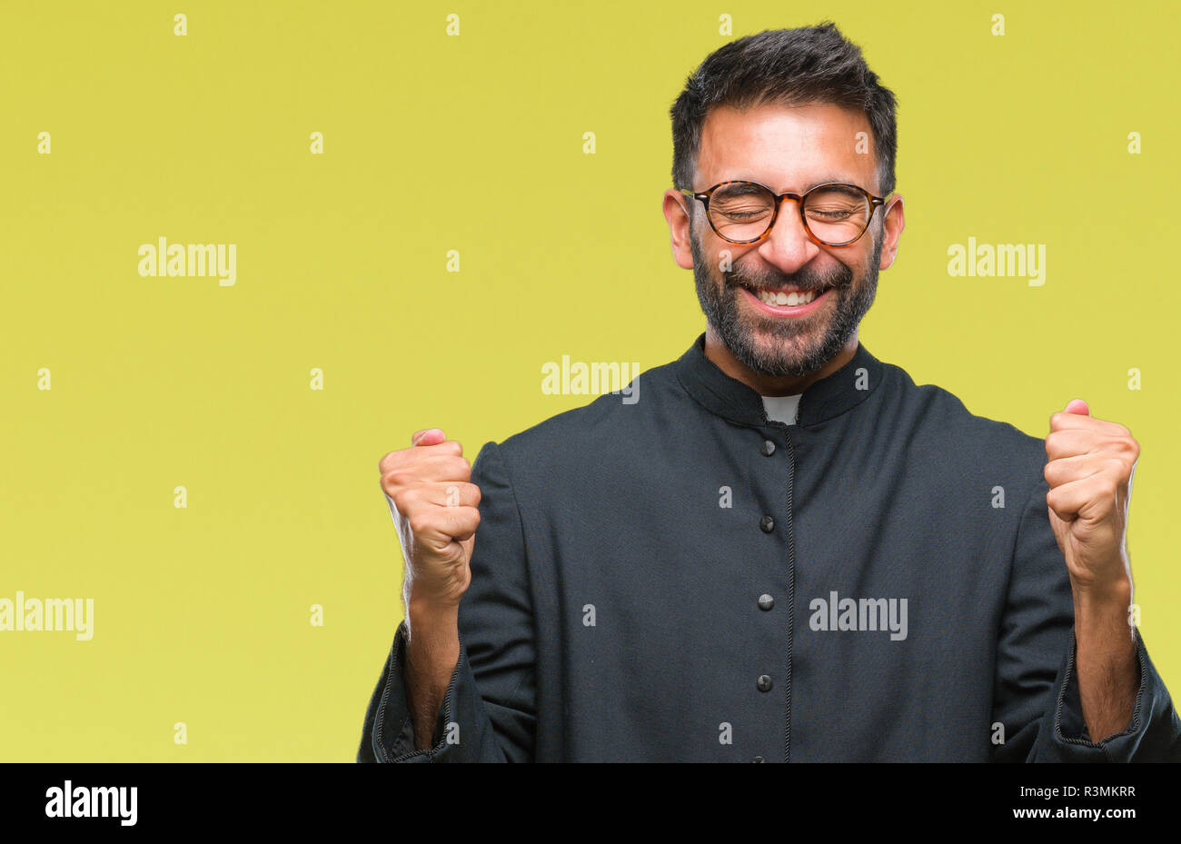 Adult hispanic catholic priest man over isolated background excited for ...