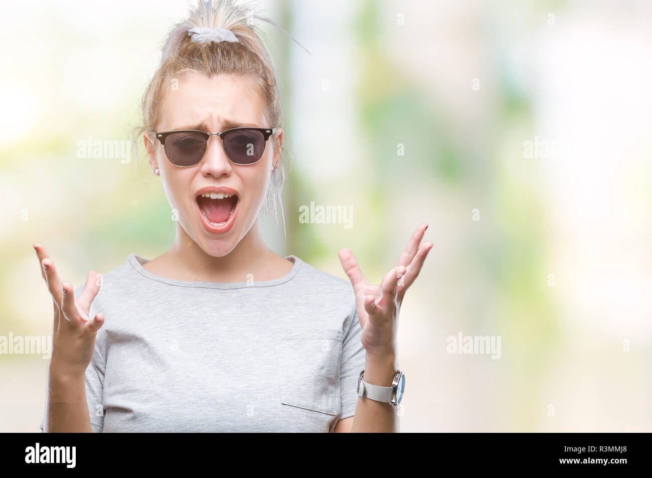 Young blonde woman wearing sunglasses over isolated background crazy ...