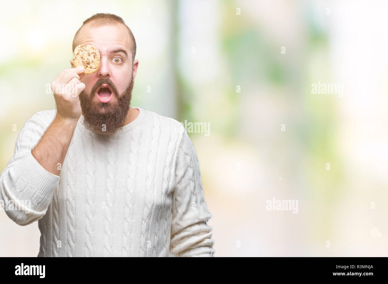 Young hipster man eating chocolate chips cookie over isolated ...