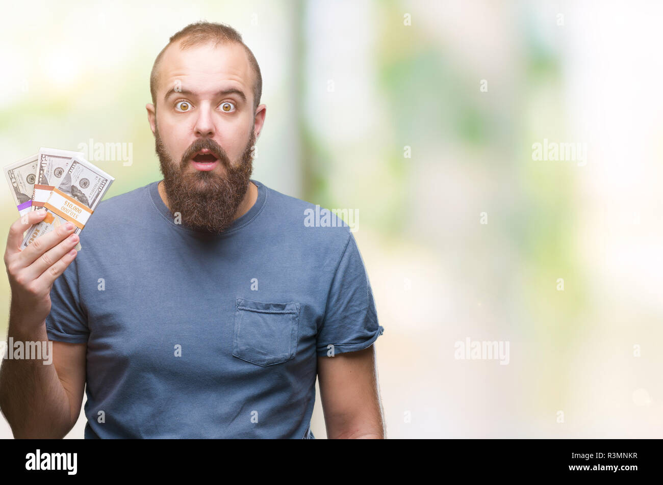 Young hipster man holding bunch of money over isolated background ...