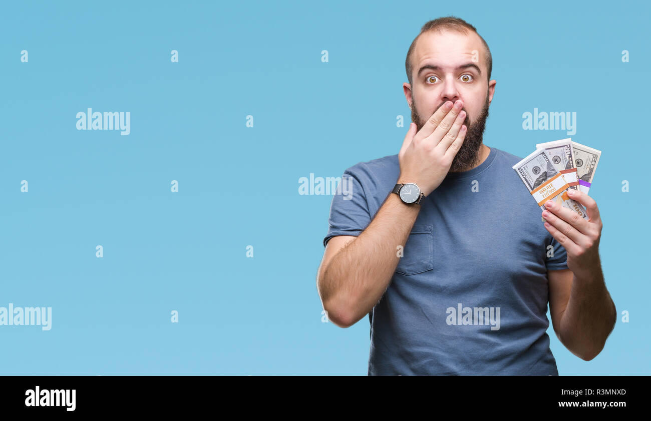 Young hipster man holding bunch of money over isolated background cover ...
