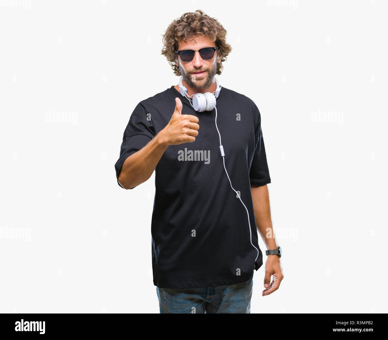 Handsome hispanic man listening to music wearing headphones over ...