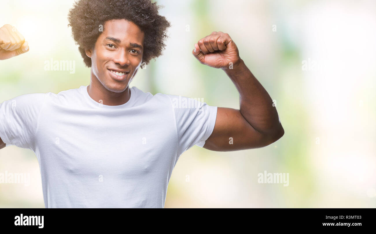 Afro american man over isolated background showing arms muscles smiling ...
