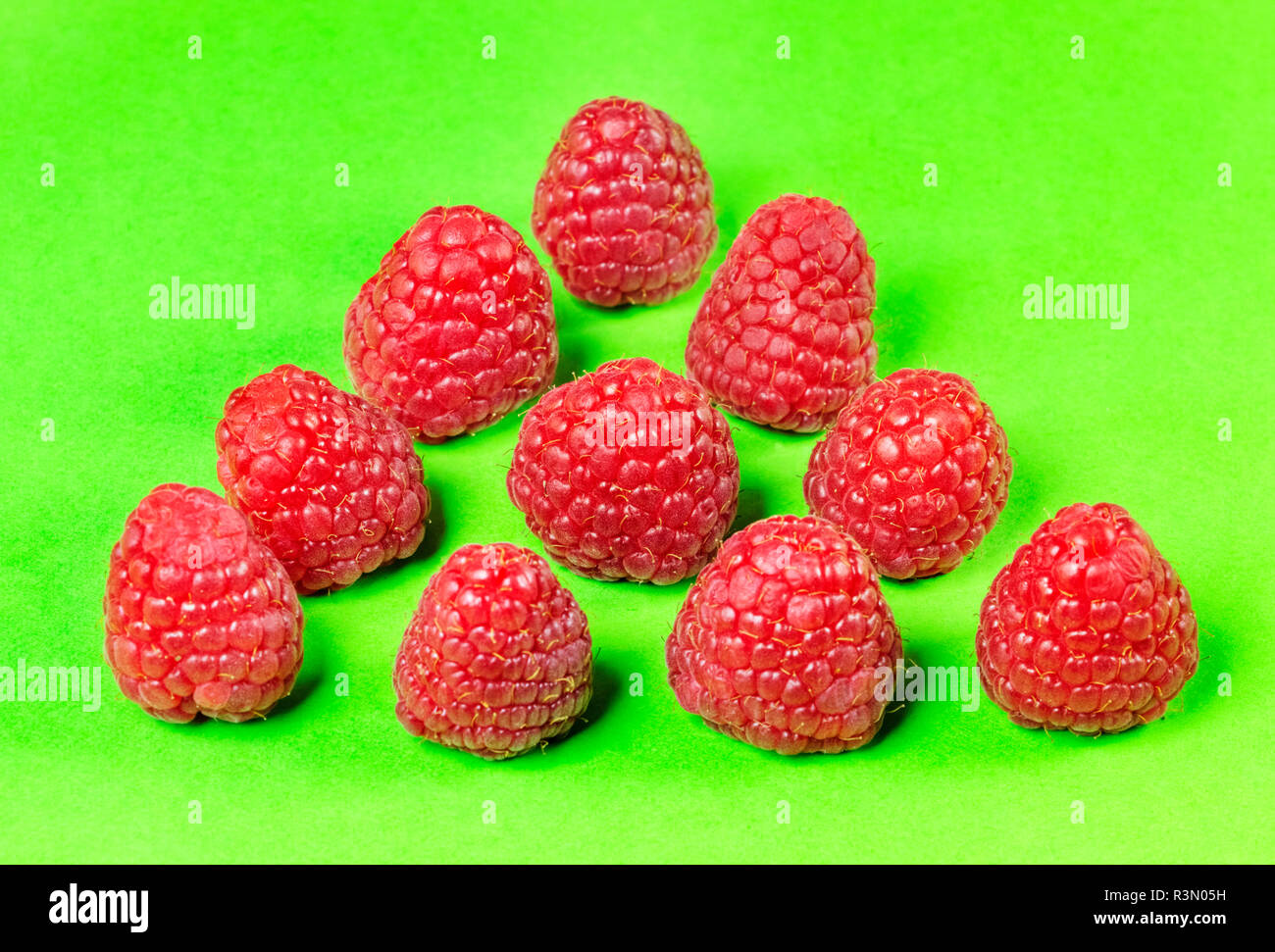 Beautiful ripe raspberries line up to form a triangle shape on a green ...
