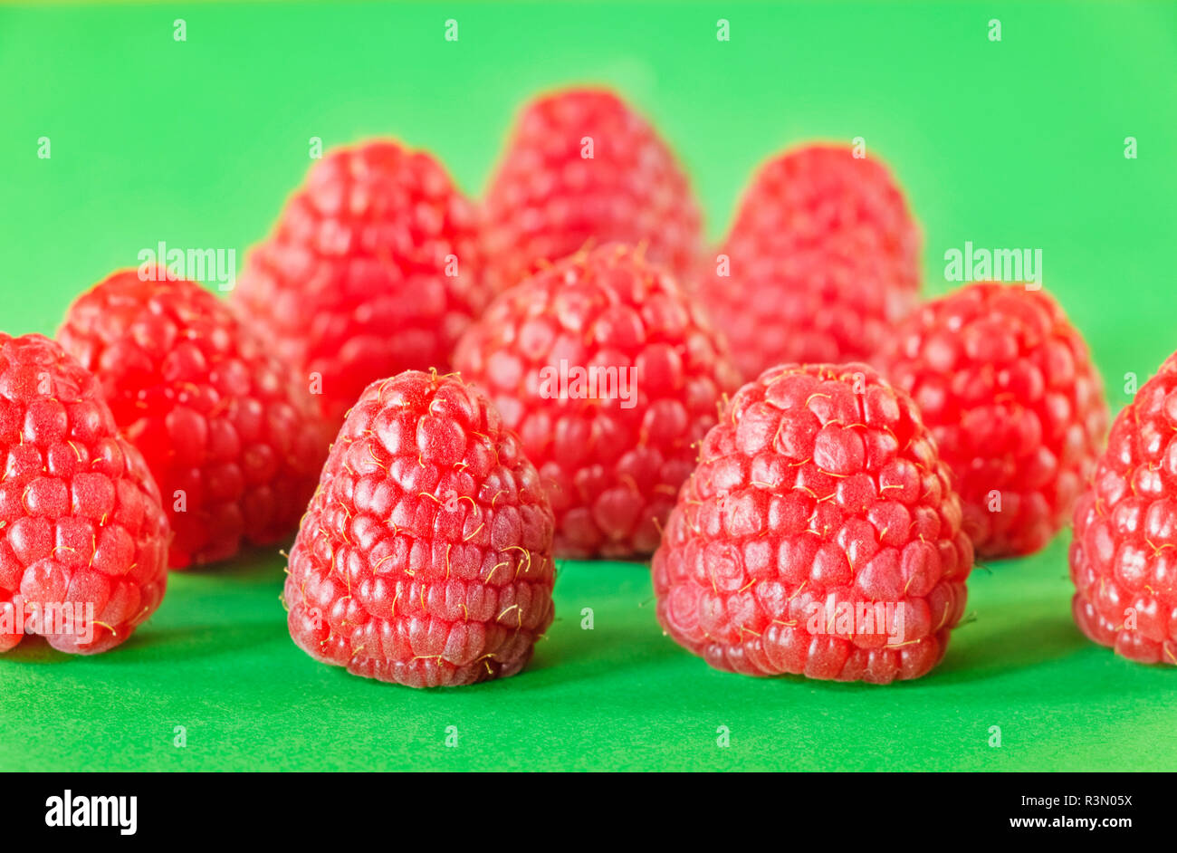 Beautiful ripe raspberries line up to form a triangle shape on a green ...