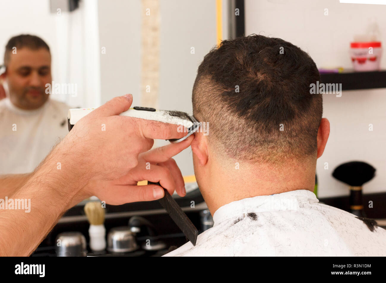 Back view of man getting short hair trimming at barber shop with a ...