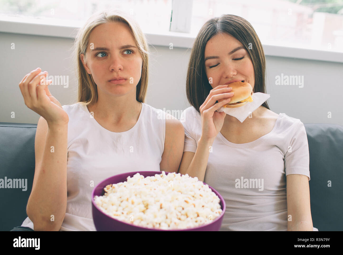 Women eating popcorn and watching tv Stock Photo - Alamy