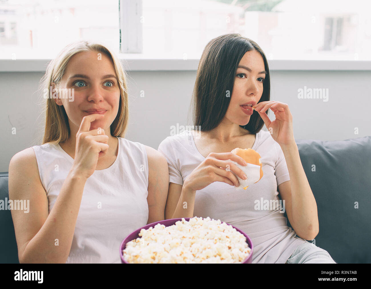 Women eating popcorn and watching tv Stock Photo - Alamy