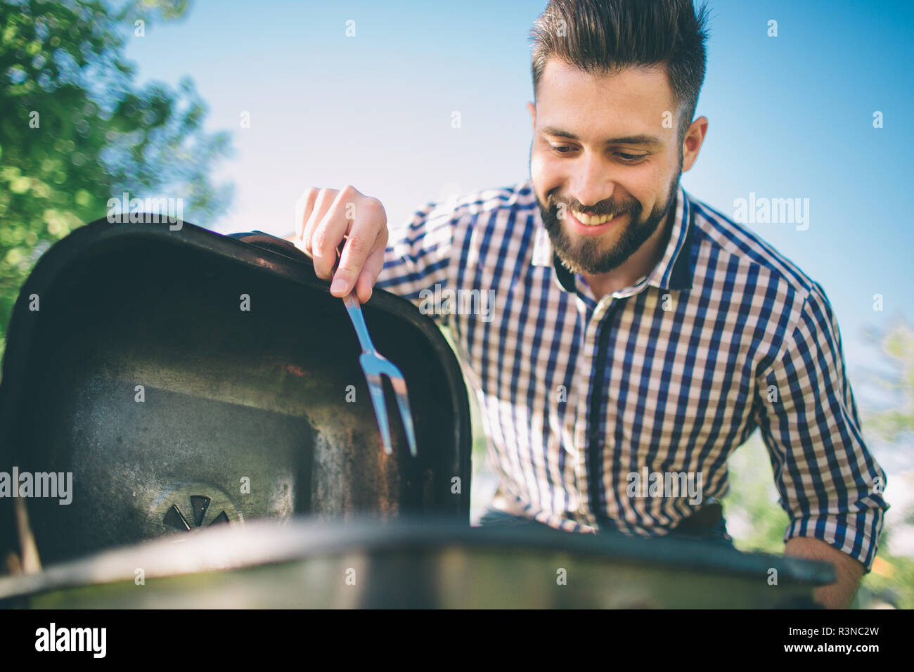 Handsome man preparing barbecue for friends. man cooking meat on ...