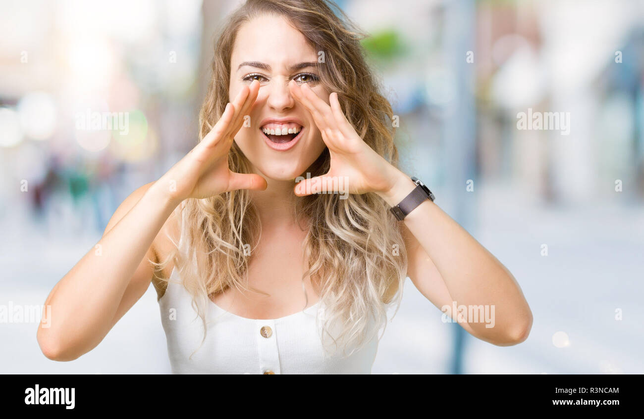 Beautiful young blonde woman over isolated background Shouting angry ...