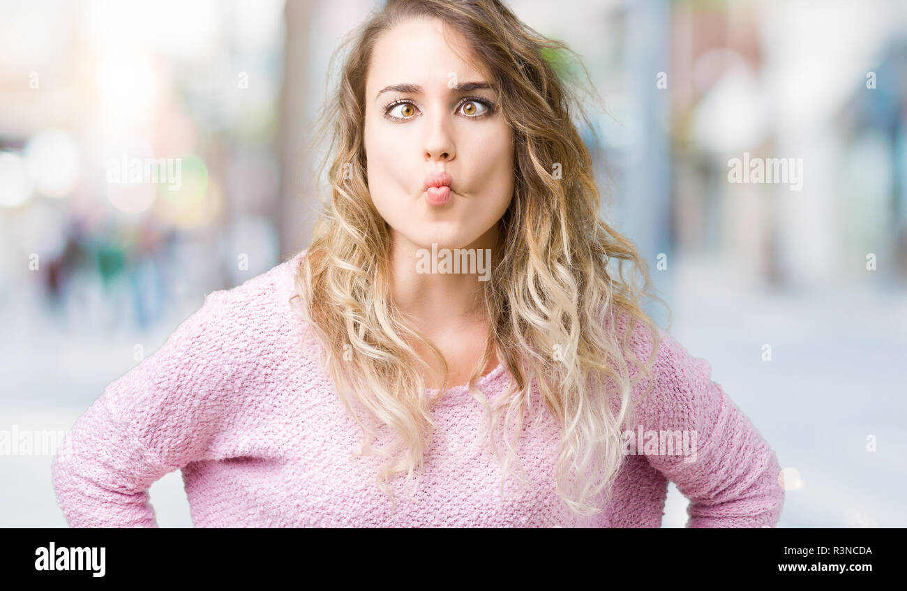 Beautiful young blonde woman over isolated background making fish face ...