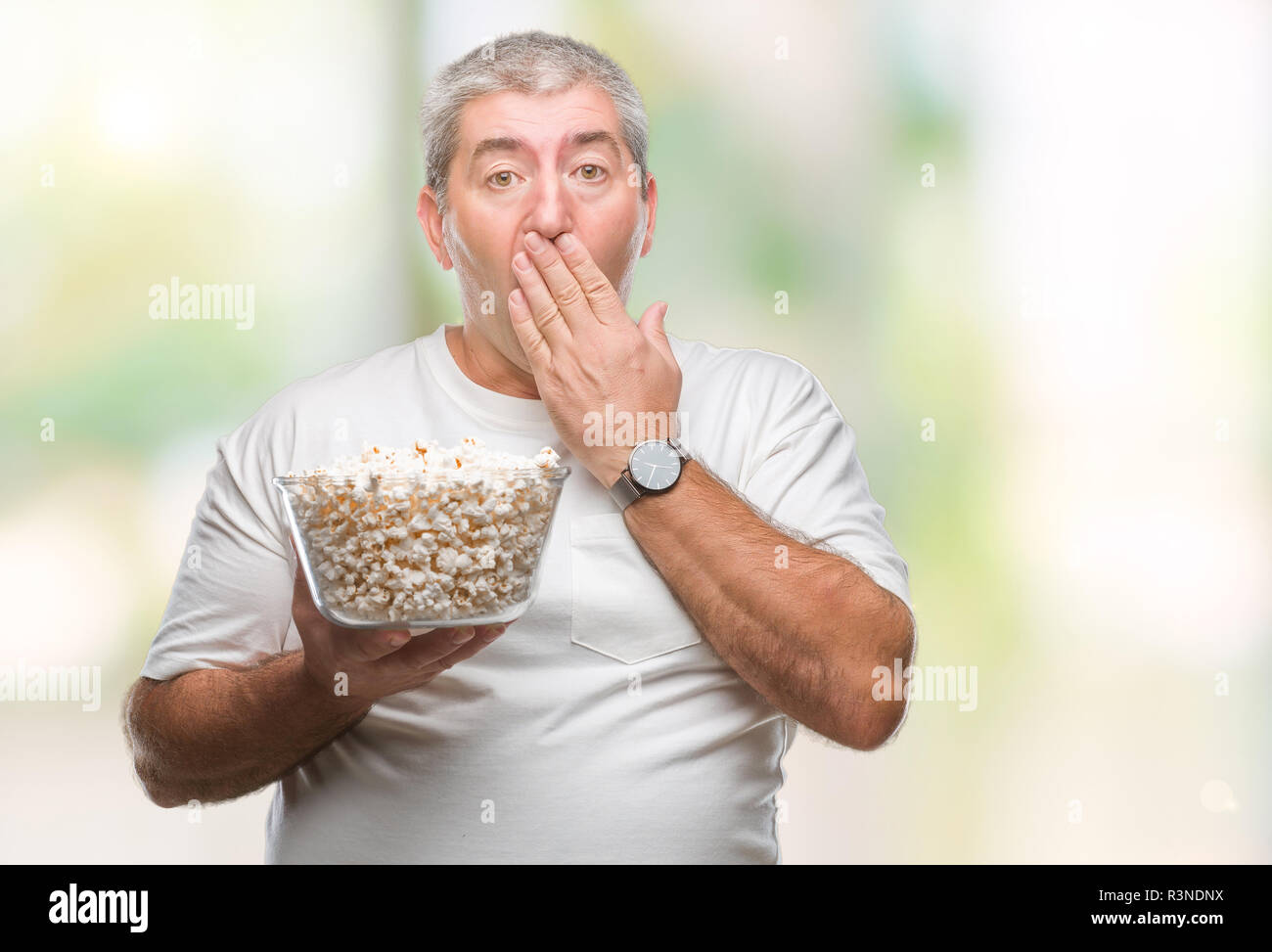 Handsome senior man eating popcorn over isolated background cover mouth ...