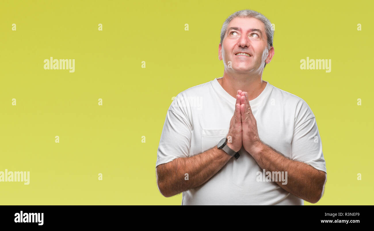 Handsome senior man over isolated background praying with hands ...
