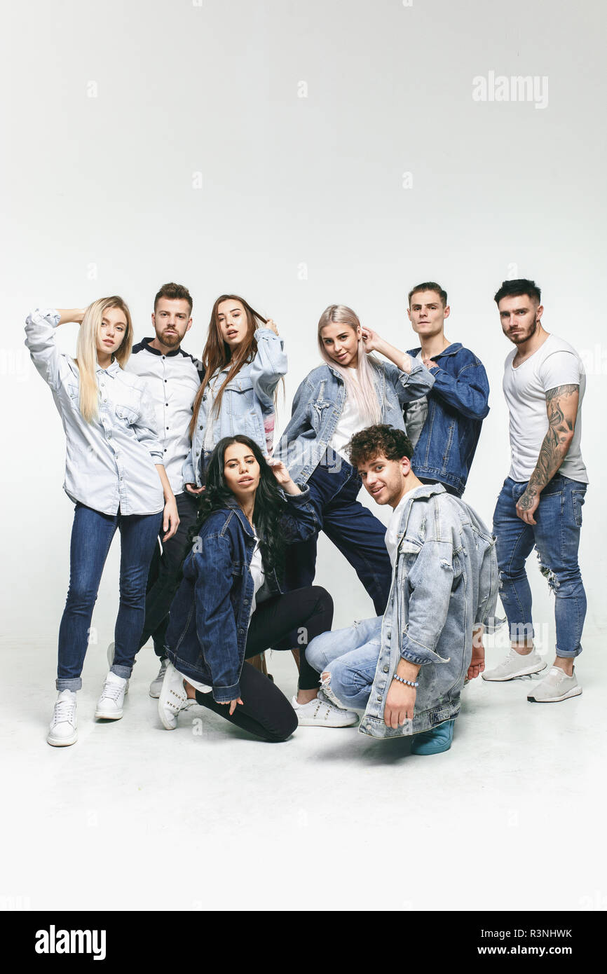 Group of smiling friends in fashionable jeans. The young men and woman ...