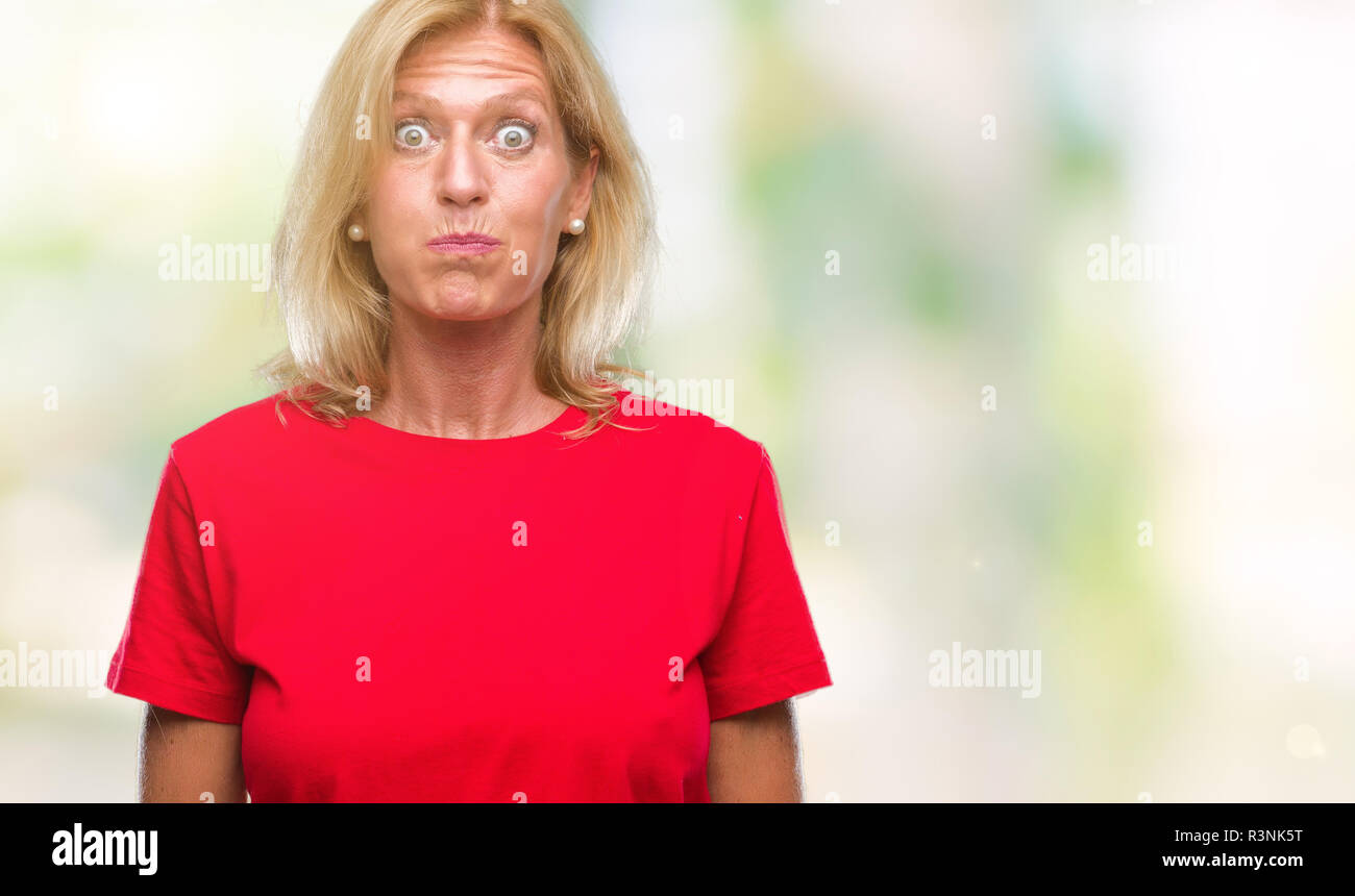 Middle age blonde woman over isolated background puffing cheeks with ...
