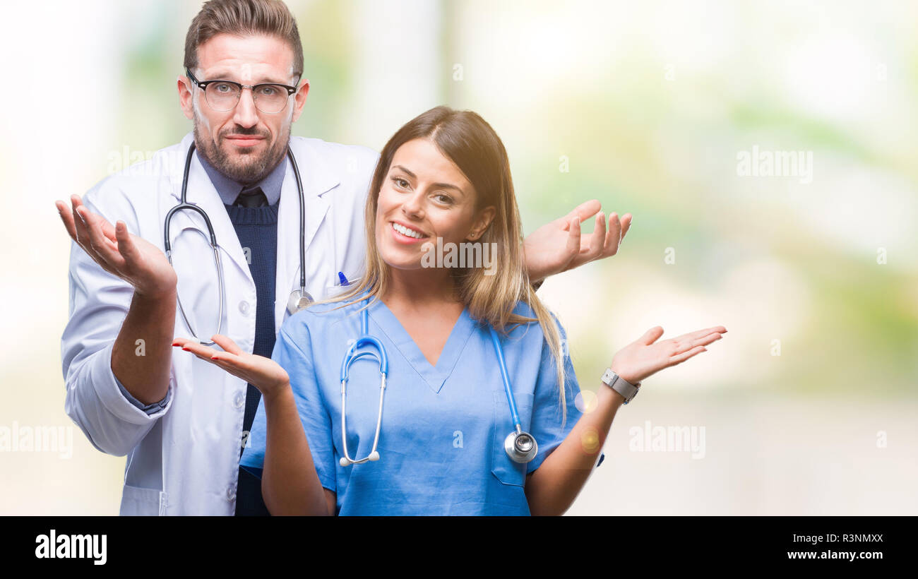 Young couple of doctor and surgeon over isolated background clueless ...