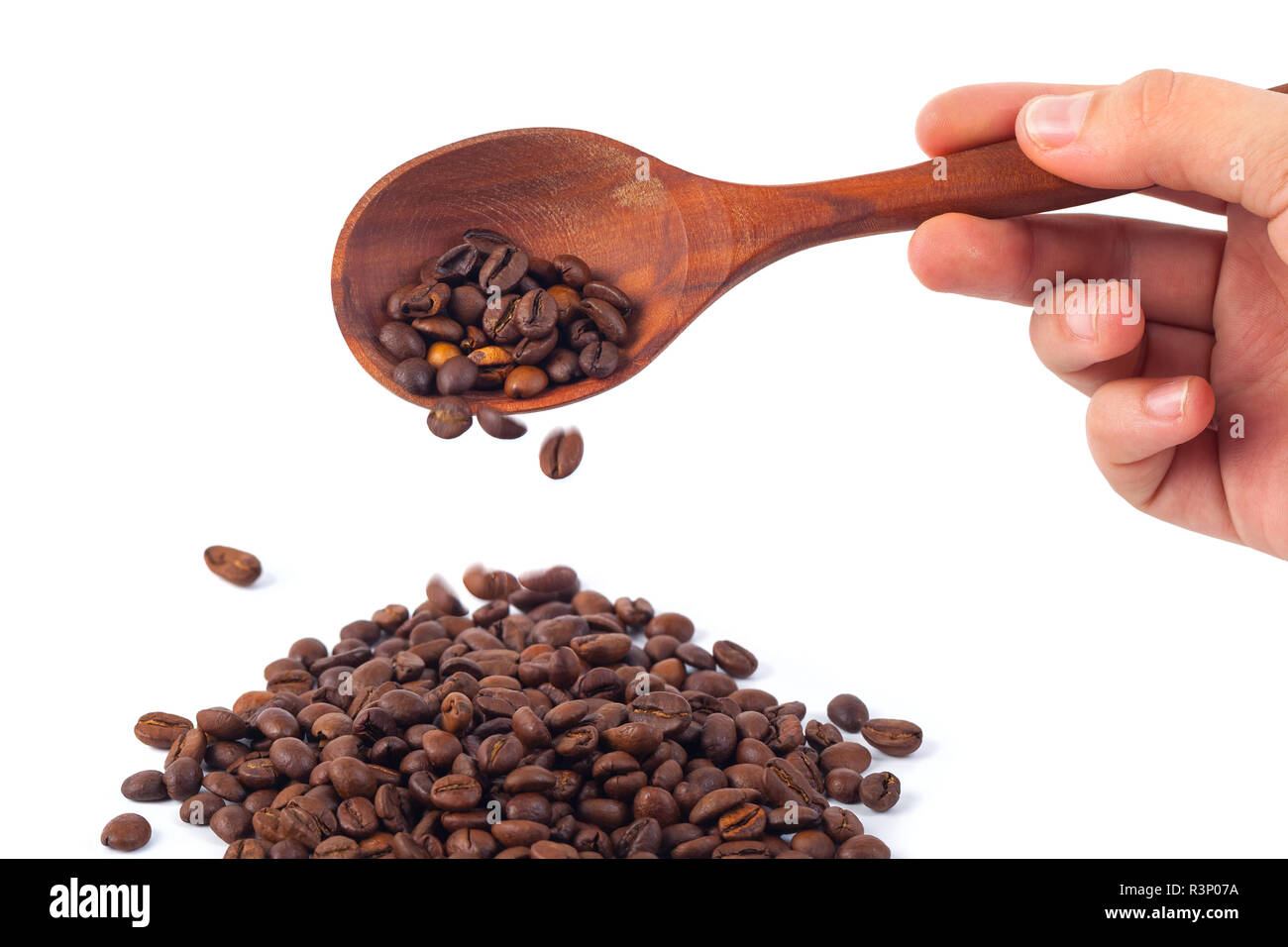 Roasted coffee beans on a wooden spoon in a womans hand on a white ...