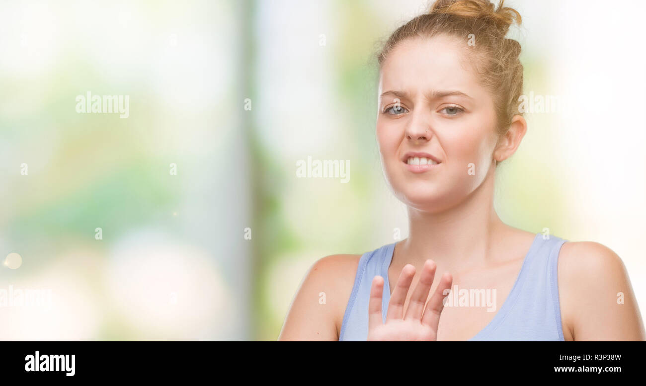 Young blonde woman disgusted expression, displeased and fearful doing ...