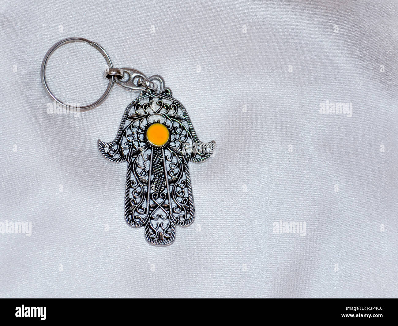 A key ring in the form of Fatima Hand on a white silk background ...