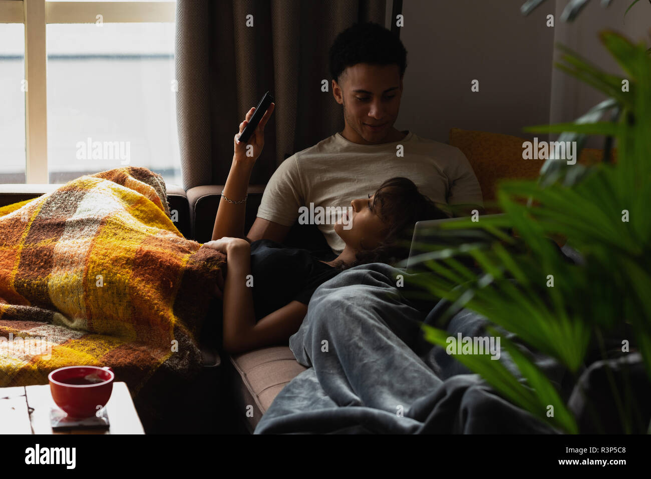 Couple using mobile phone on sofa in living room Stock Photo - Alamy