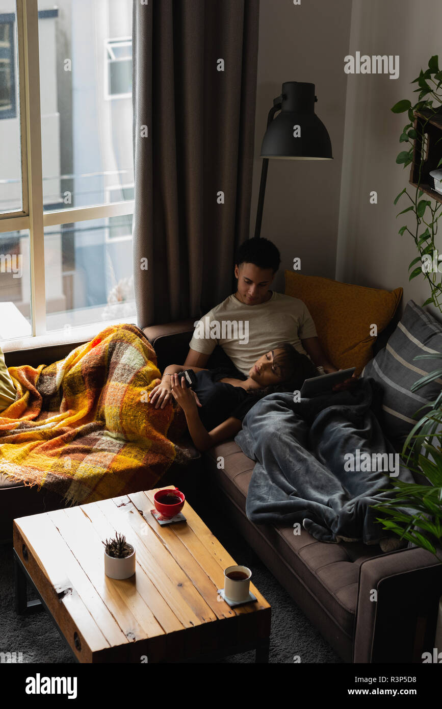 Couple relaxing on sofa in living room Stock Photo - Alamy