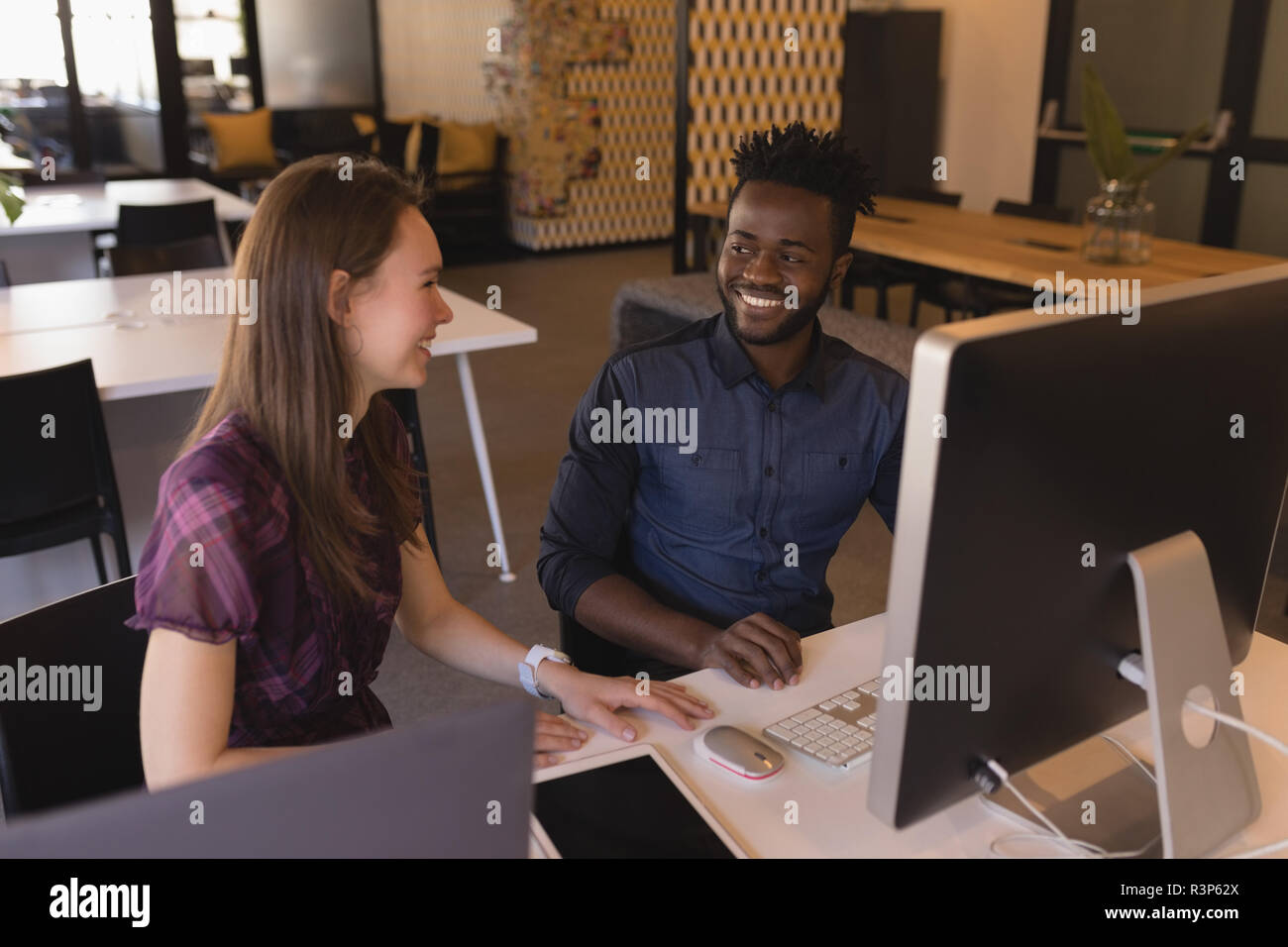 Business colleagues interacting with each other at desk Stock Photo - Alamy