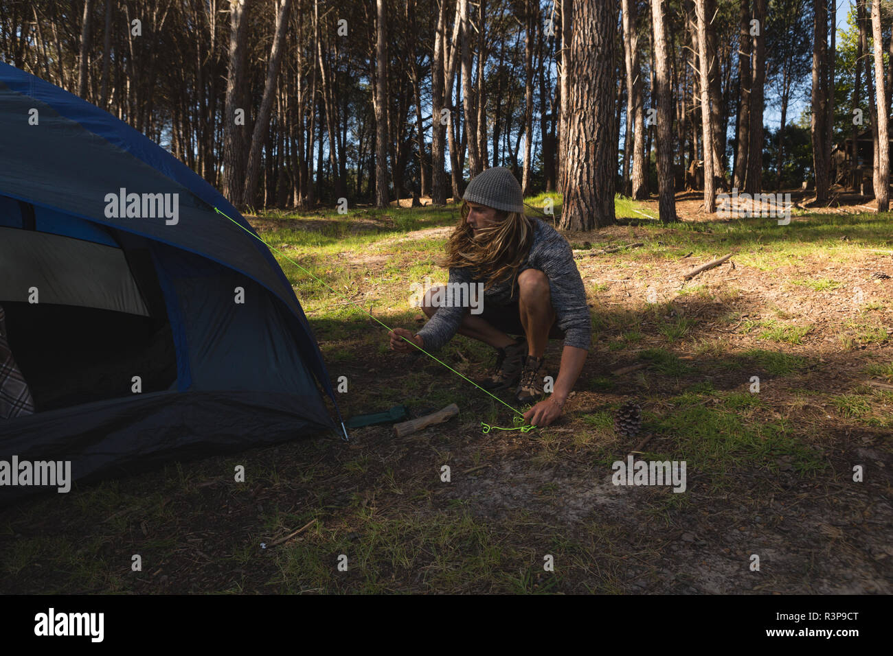 Man putting up a tent in the forest Stock Photo - Alamy
