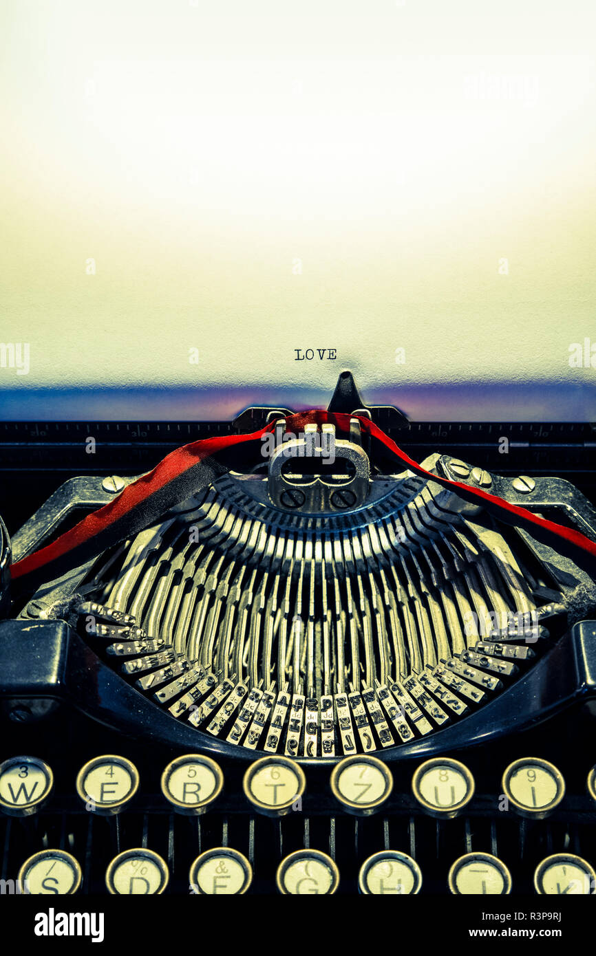 ancient old portable typewriter with love font on paper in portrait ...