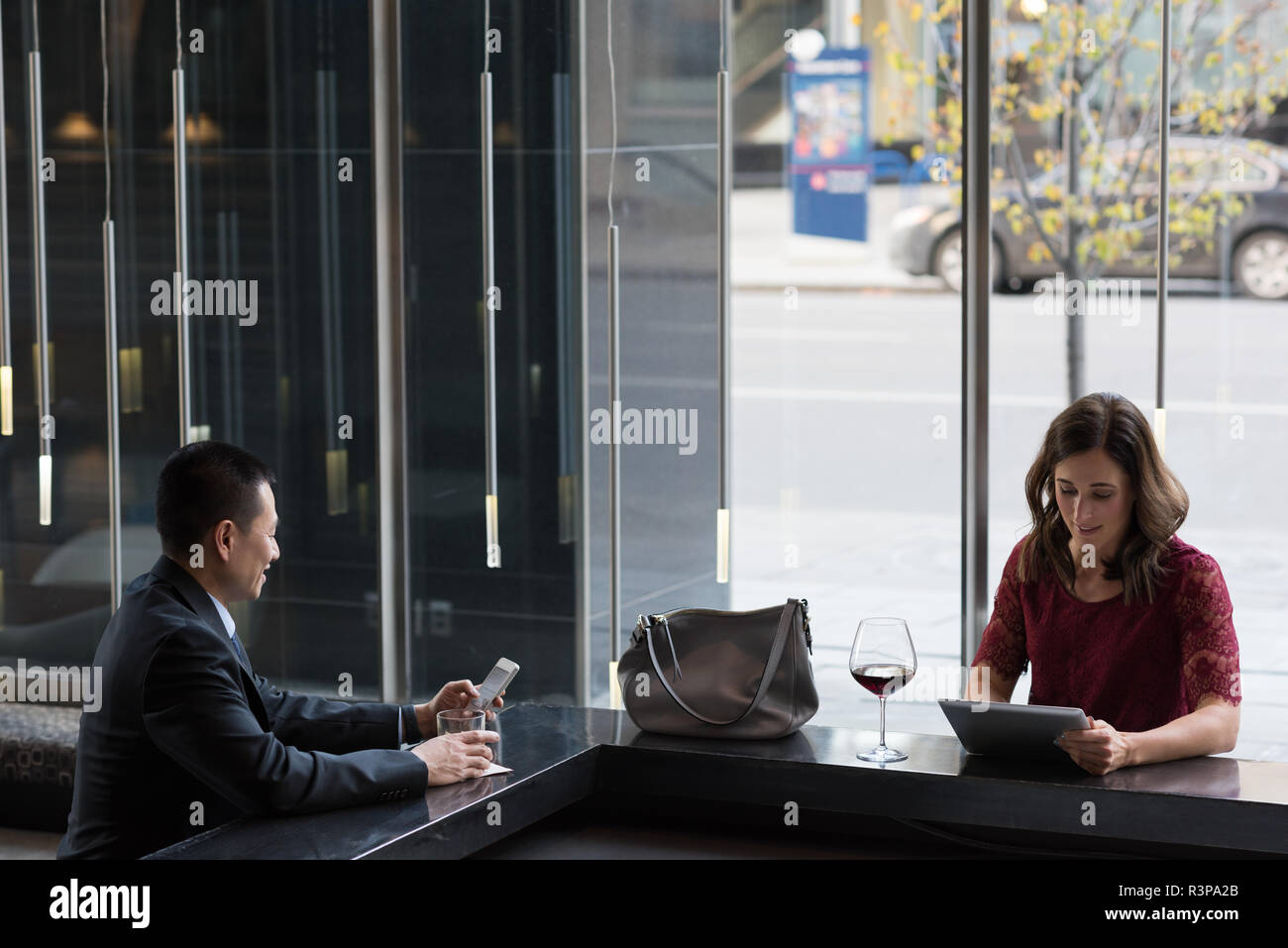 Business people using mobile phone and digital tablet at bar counter ...