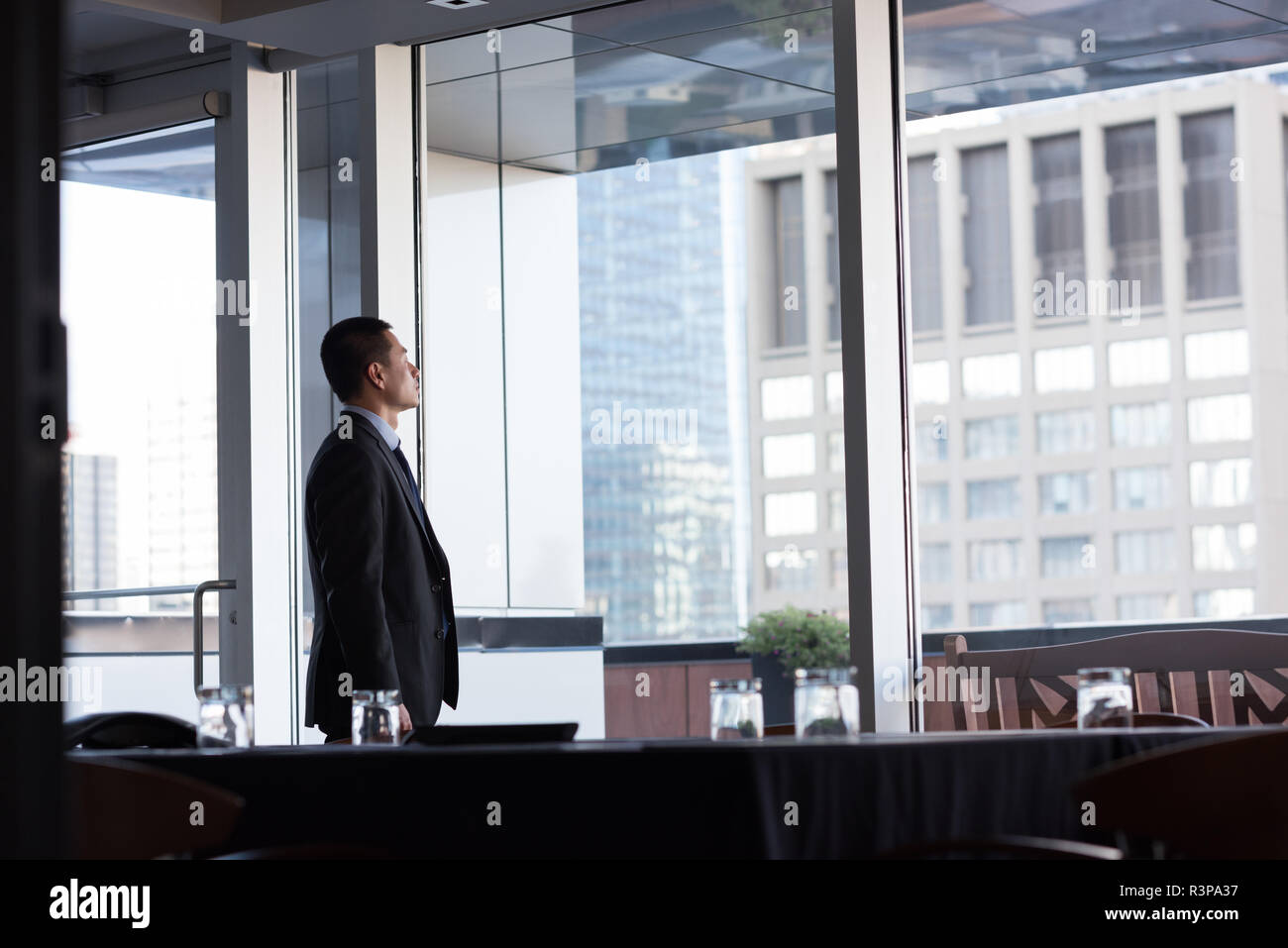 Businessman looking through window in conference room Stock Photo - Alamy