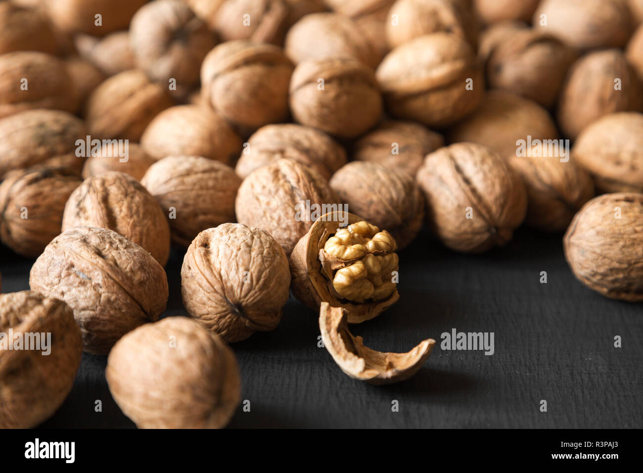Halved and whole walnuts on black background, side view. Close-up ...