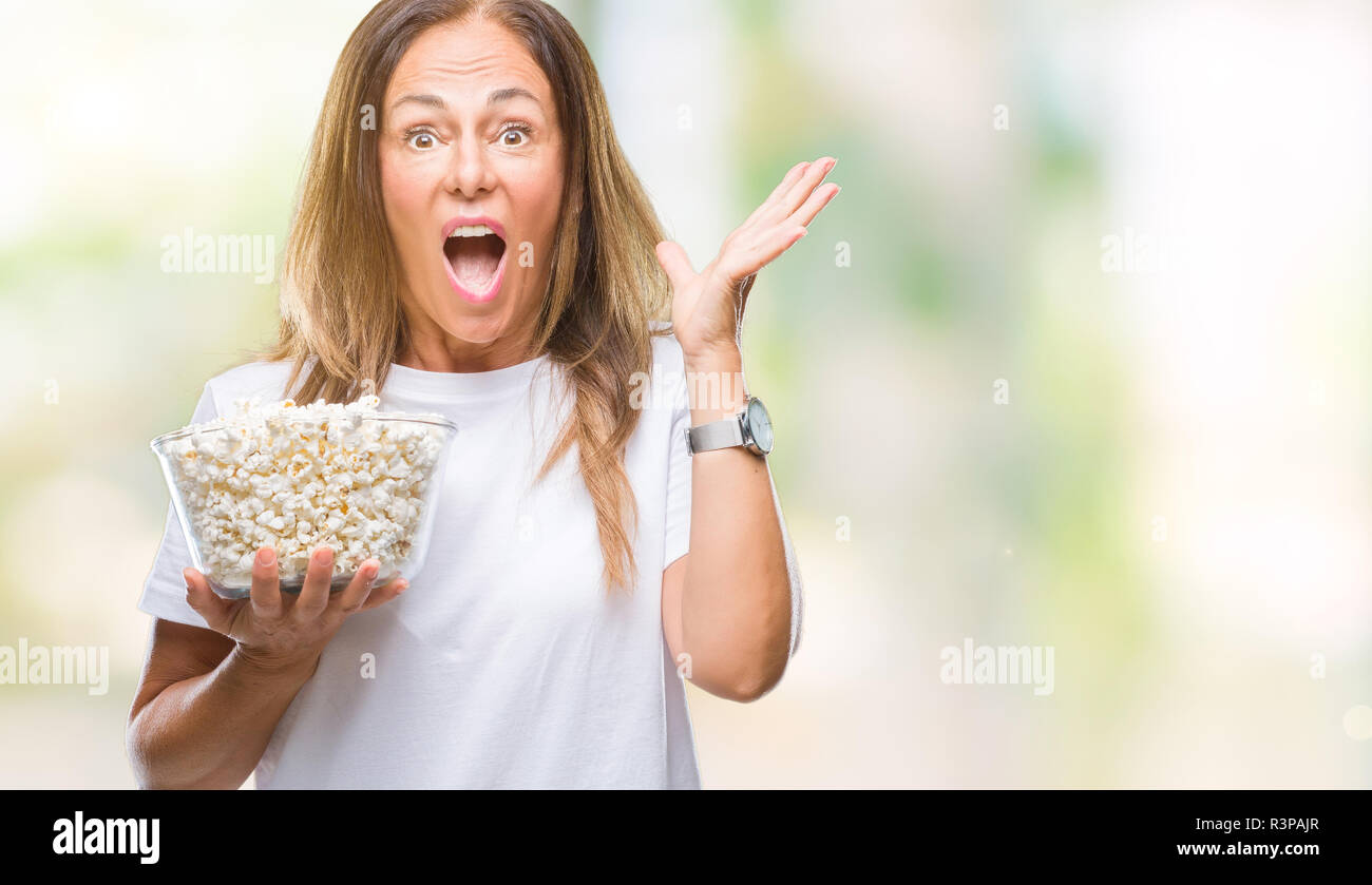 Middle age hispanic woman eating popcorn over isolated background very ...
