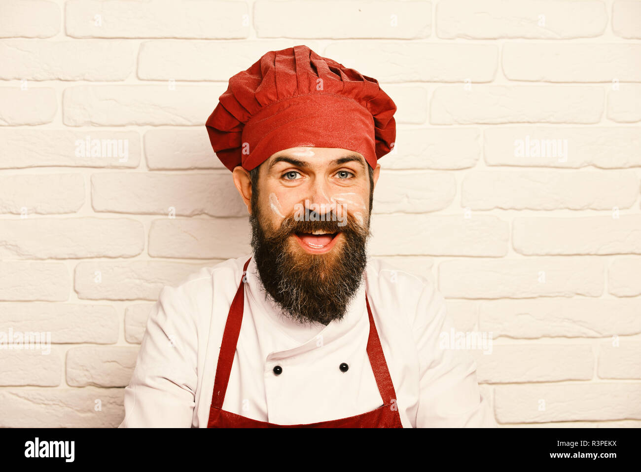 Man with happy face in white brick wall background, close up. Cook with ...