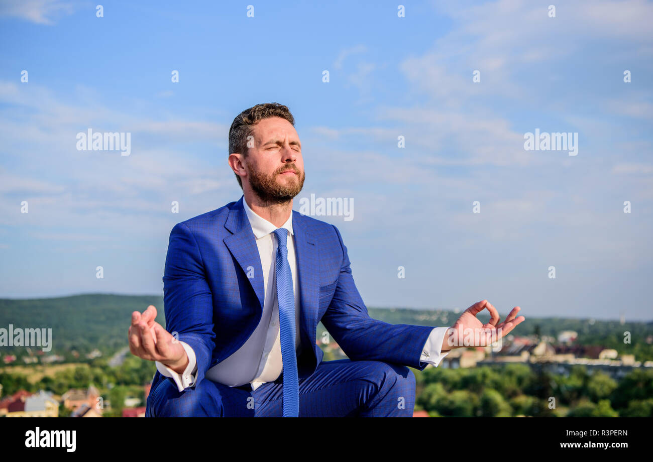 Businessman formal suit sit lotus pose and meditating outdoors. Man try ...