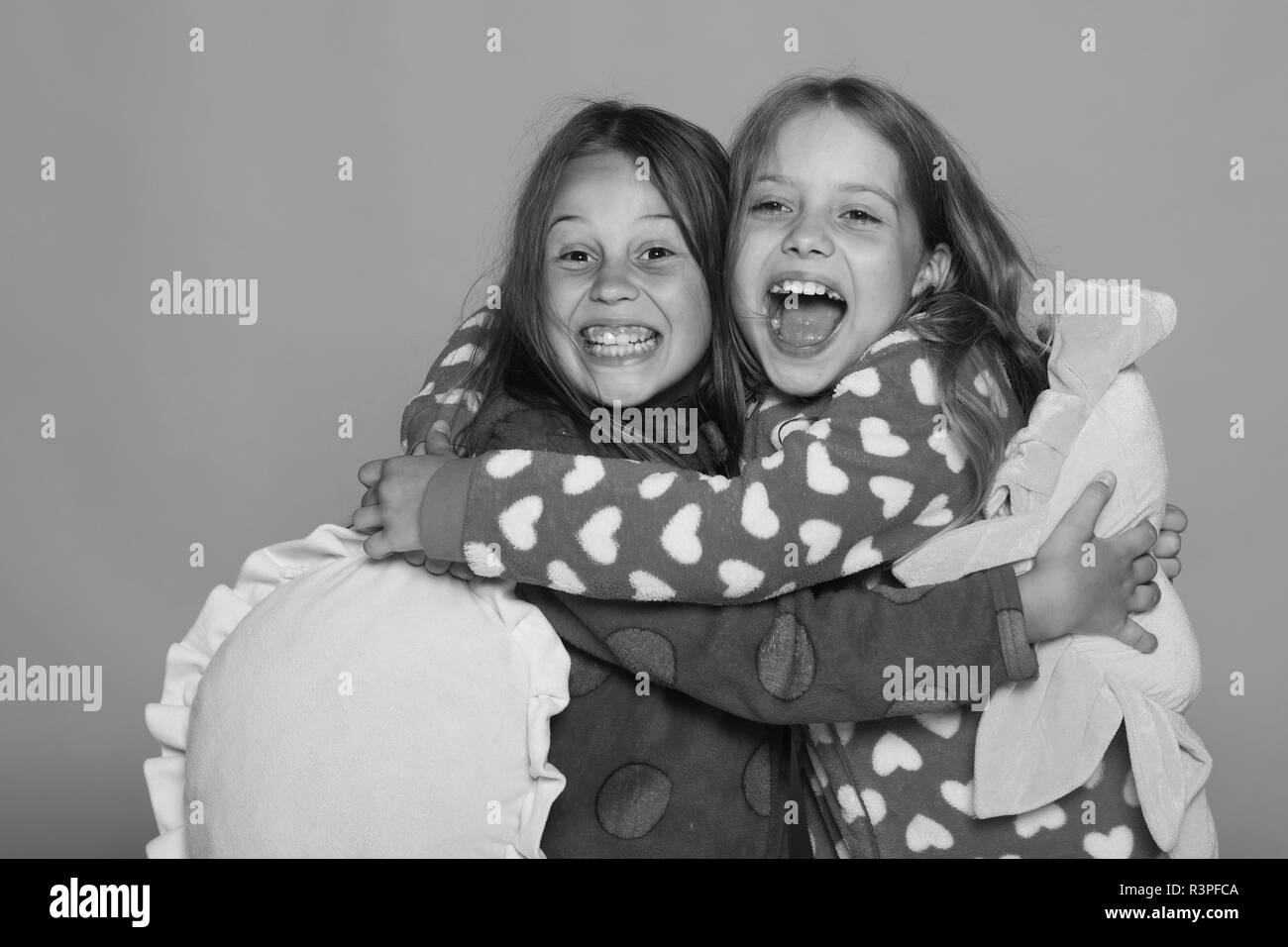 Girls in colorful polka dotted pajamas hold funny bright pillows ...