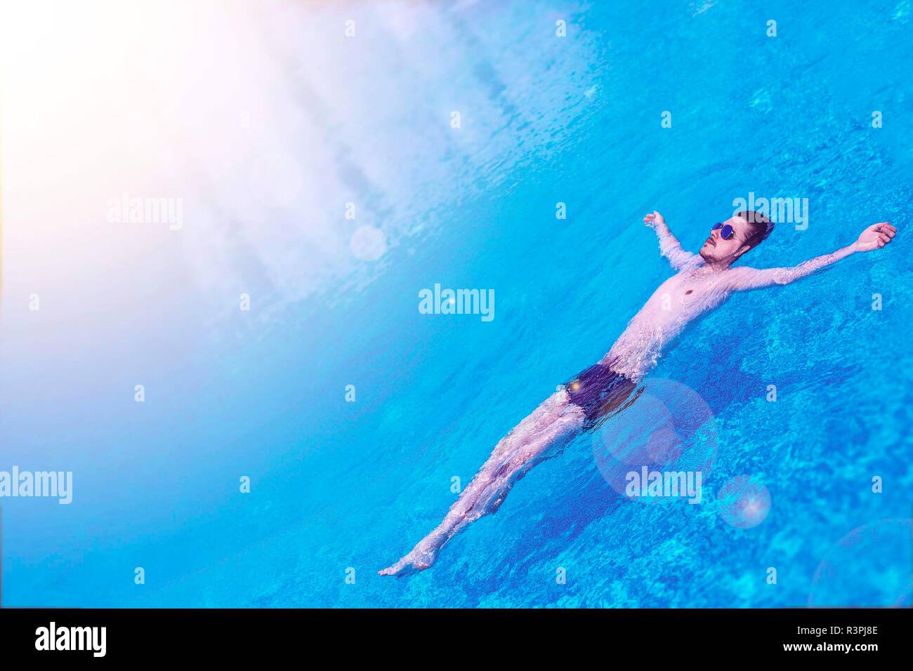 Man floating on the water in the swimming pool. Male swim in the pool ...