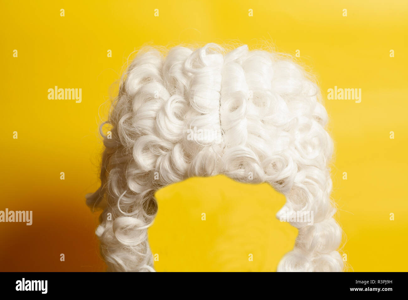 Judge white wig on a yellow background Stock Photo - Alamy