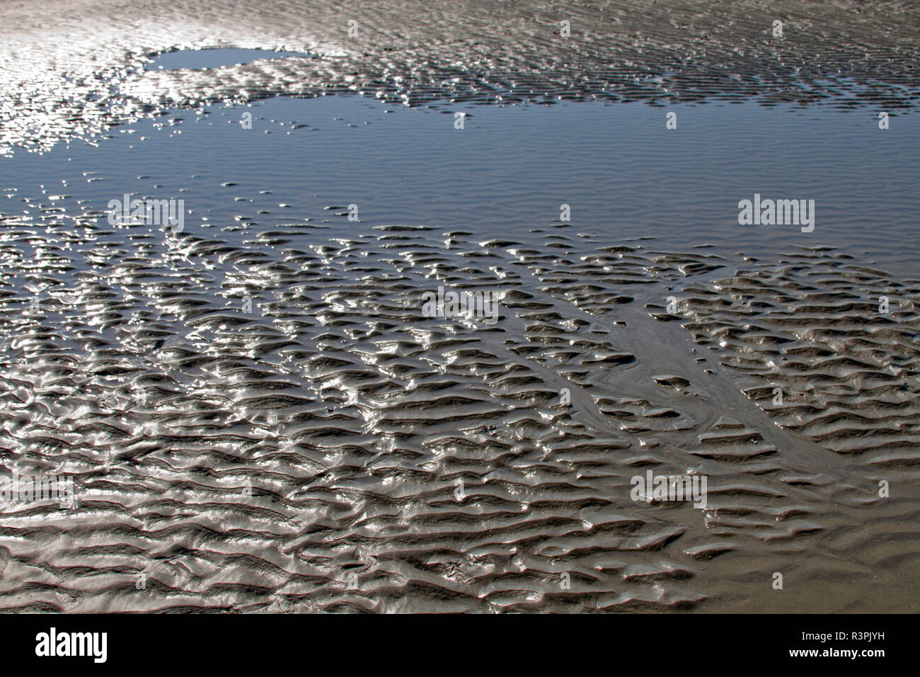 A scenic, shallow, tide pool by the sea with ripples textured by the ...