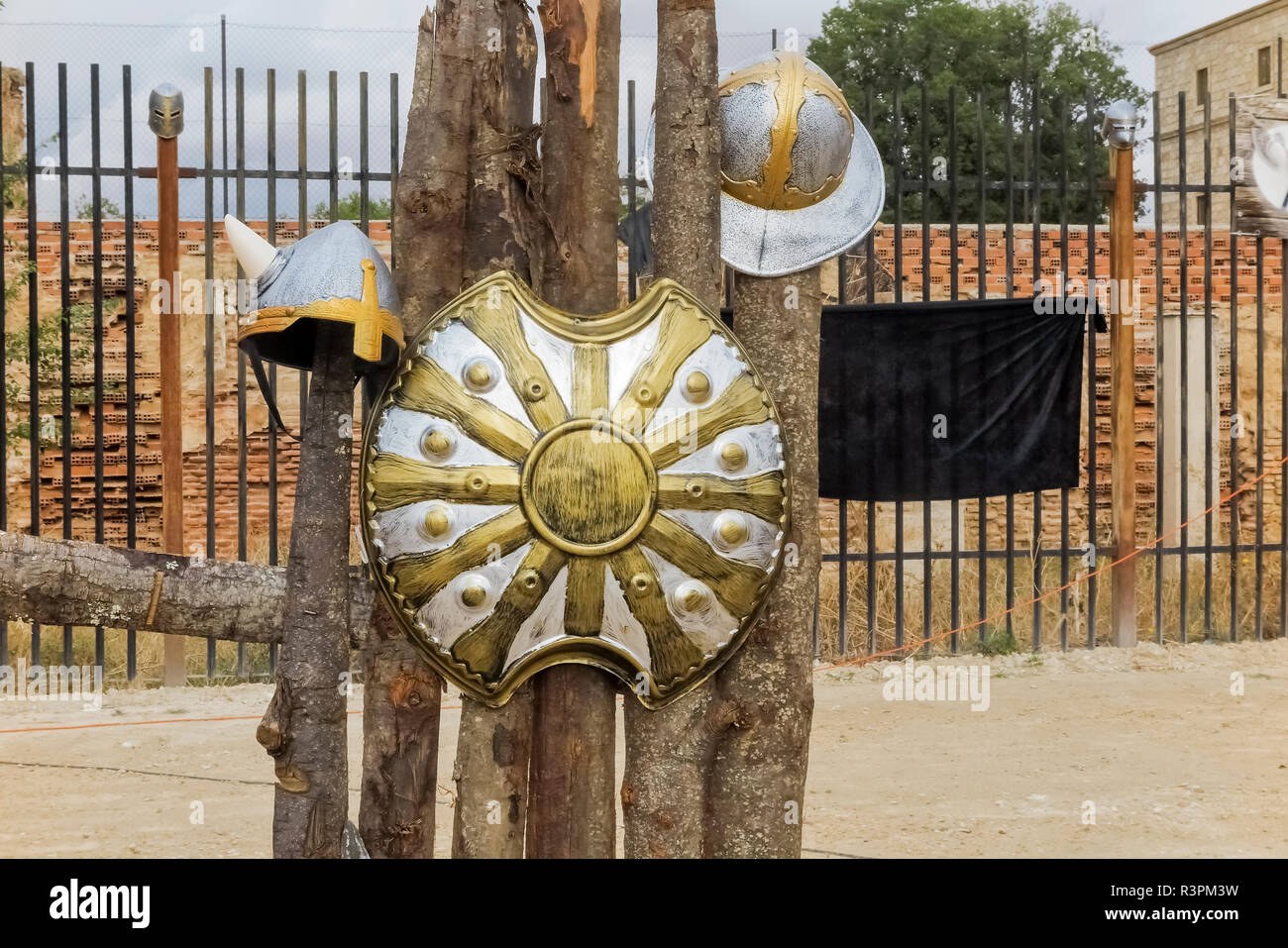 foreground of a medieval rounded shield and two medieval helmets over ...