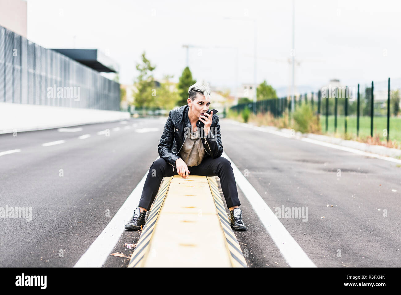 Punk woman sitting at the roadside using cell phone Stock Photo - Alamy
