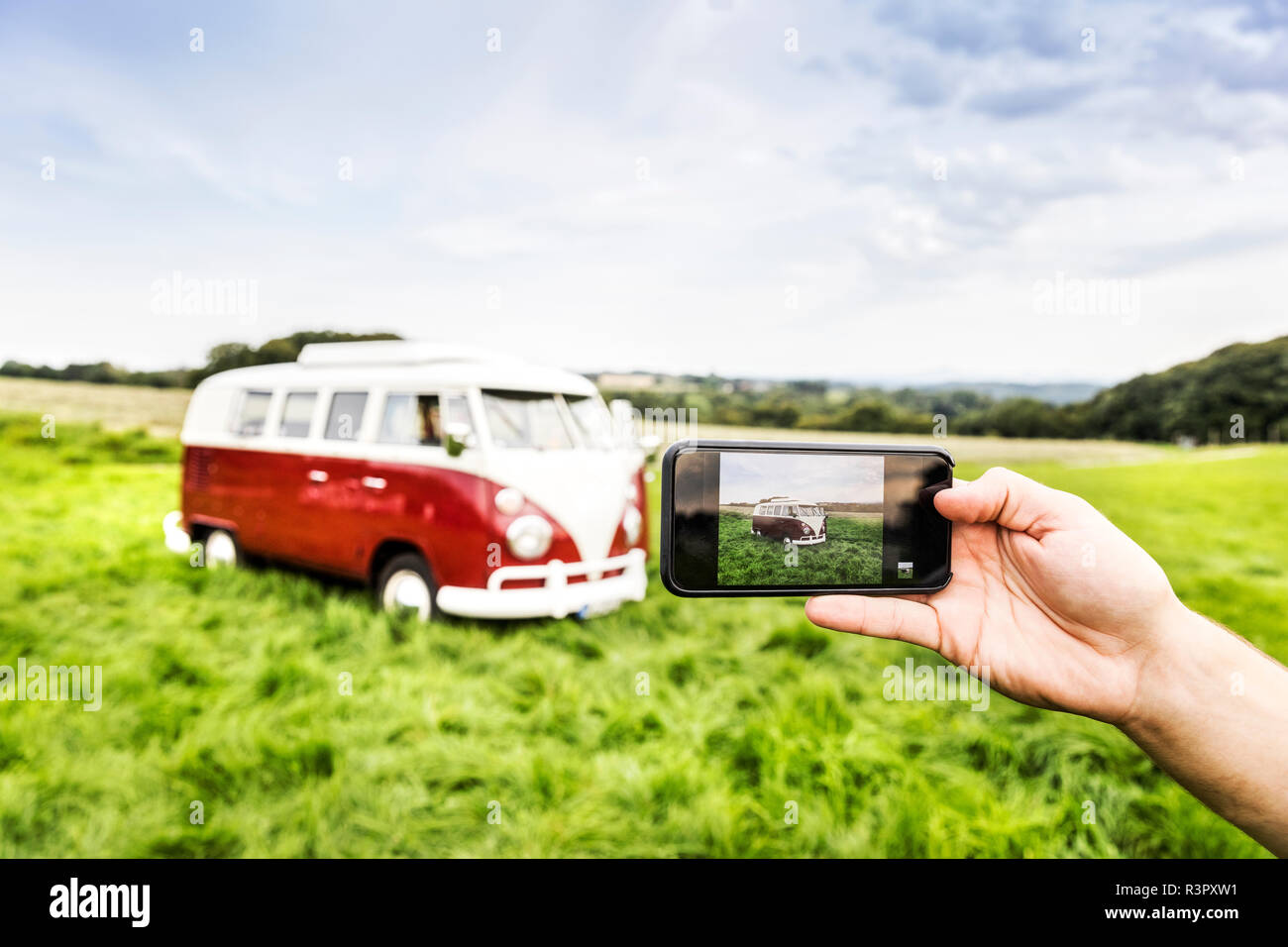 Woman's hand taking cell phone picture of van in rural landscape Stock ...