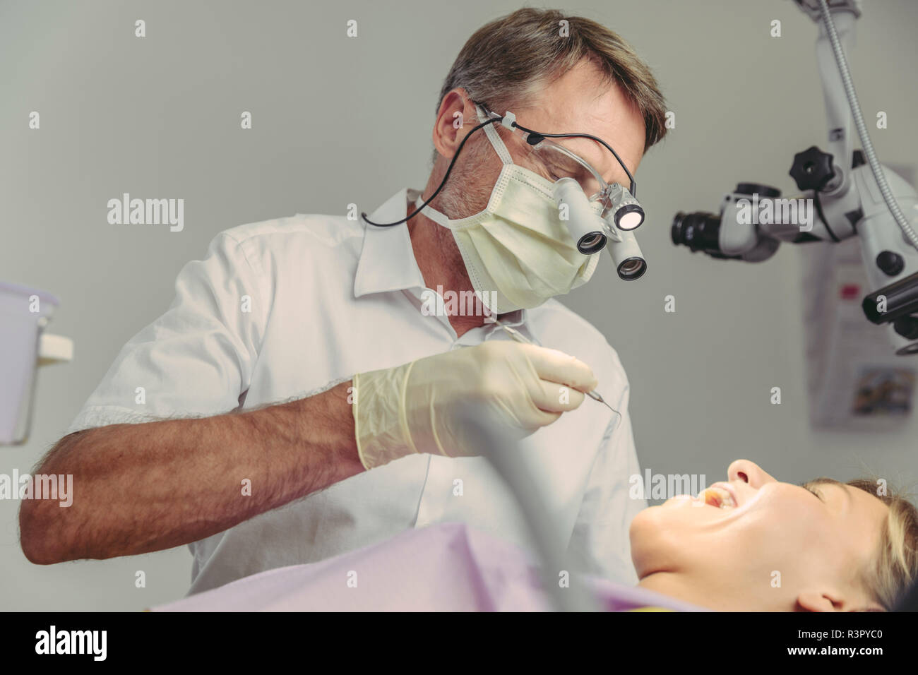 Dentist examining his patient, using dental microscope Stock Photo - Alamy