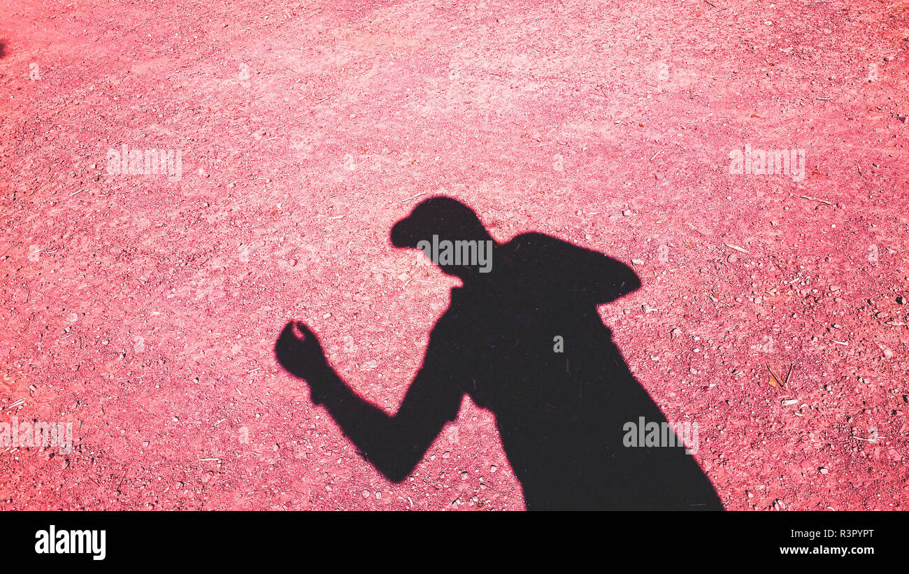 Shadow on the ground of a runner with a cap in summer with a lot of ...